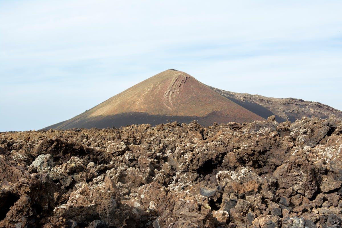 Rocky volcanic terrain stretching across Lanzarote with scattered dark lava rocks under cloudy skies