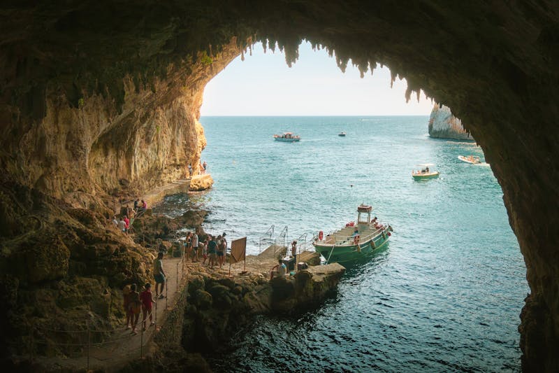 Tourists on a boat entering a sea cave in Puglia Italy with turquoise water