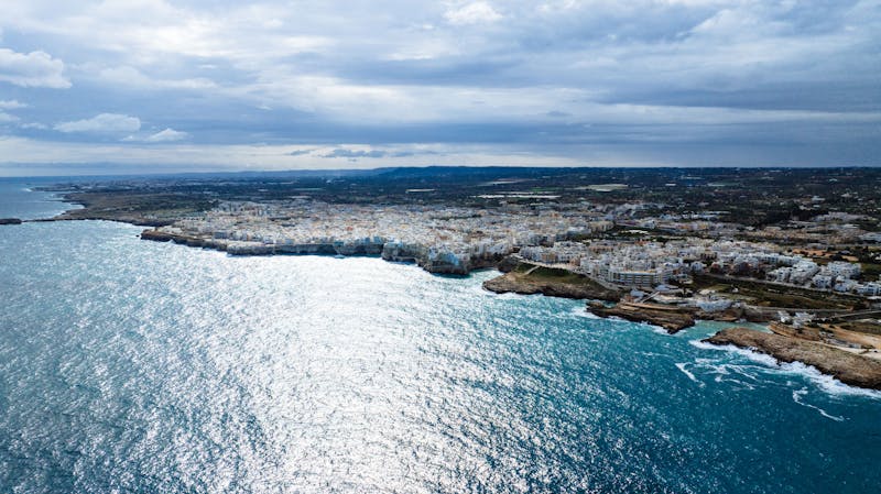 Panoramic aerial view of Polignano a Mare coastline showing the town, beaches, and crystal blue waters