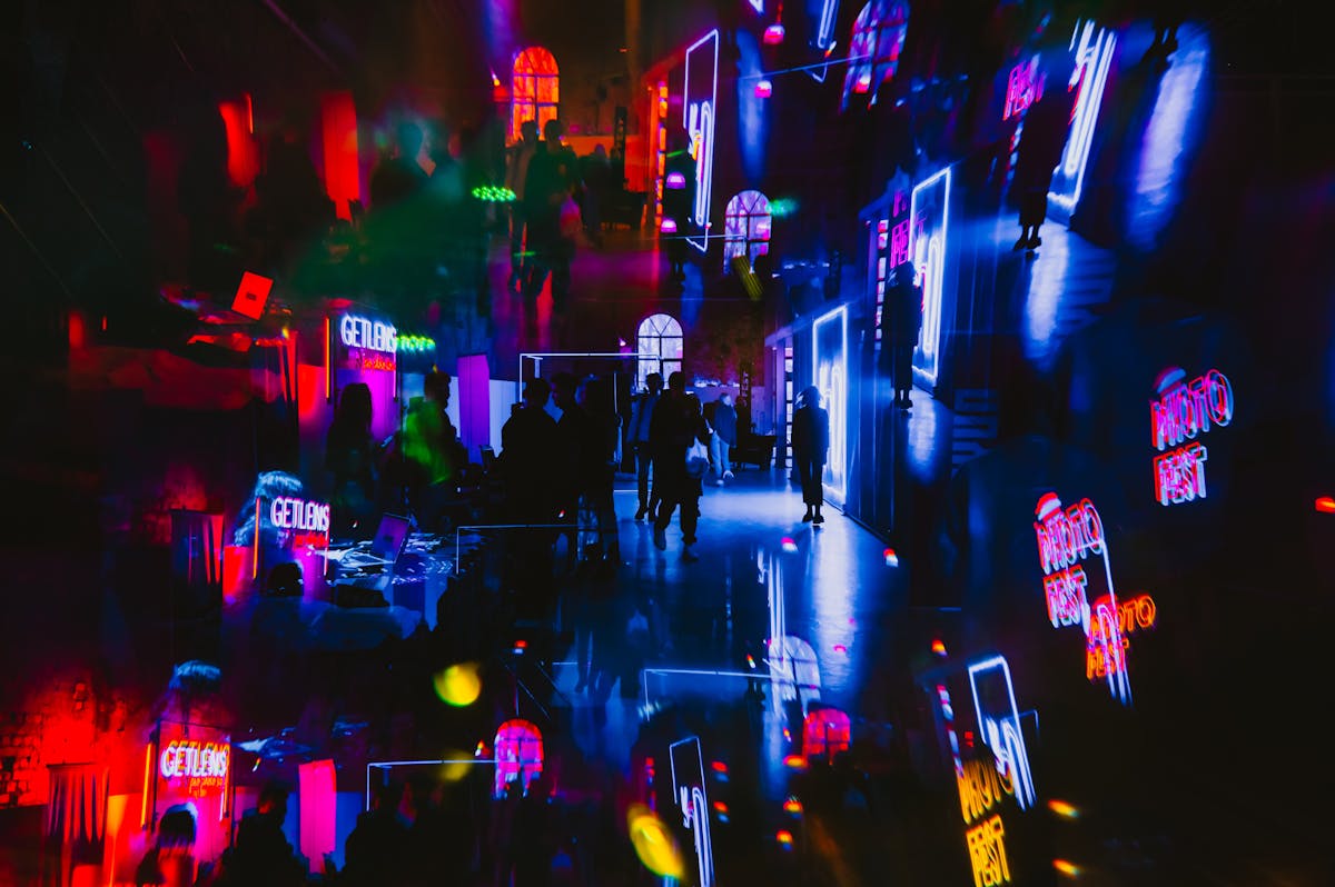 A colorful art gallery with kaleidoscopic neon lights and visitors enjoying a party atmosphere