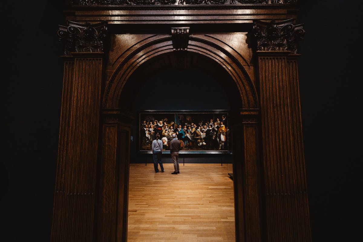 Two visitors viewing a historic painting in an Amsterdam museum gallery