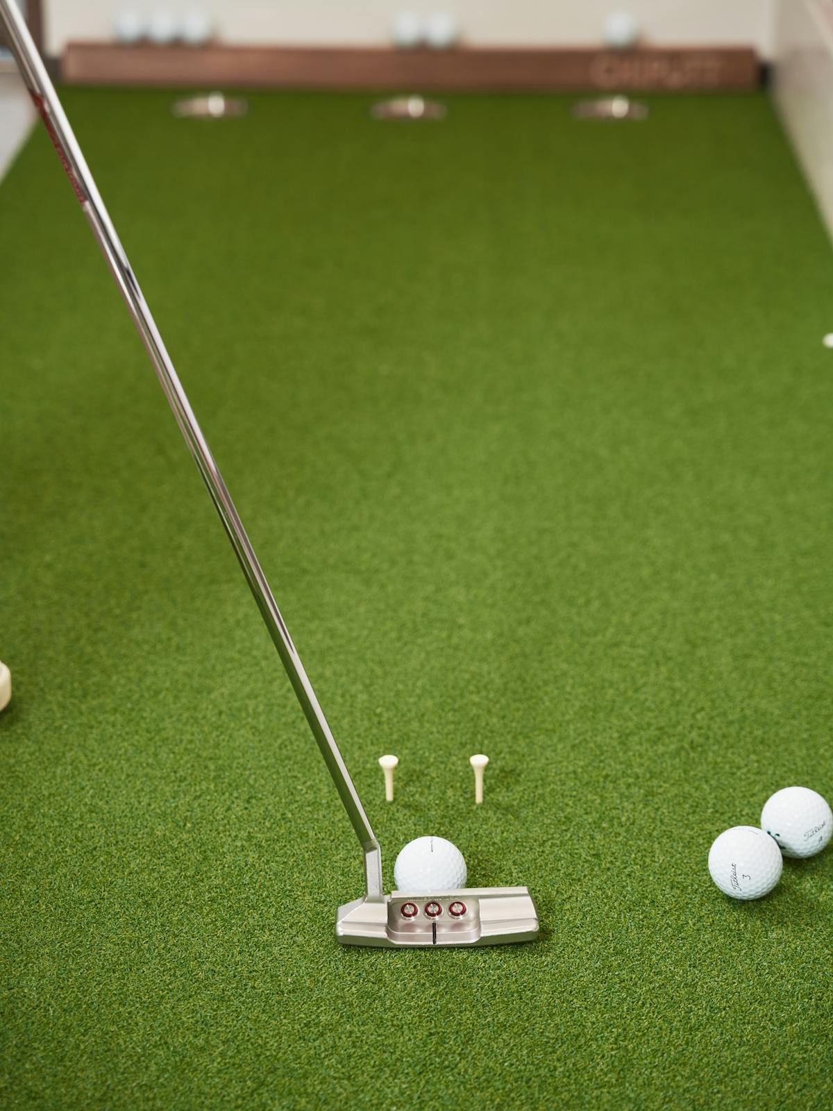 Close-up of a putter and golf balls on a putting green