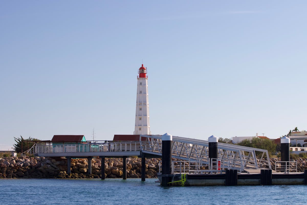 The Farol Island Lighthouse at the coastline in Faro Portugal during a clear summer day