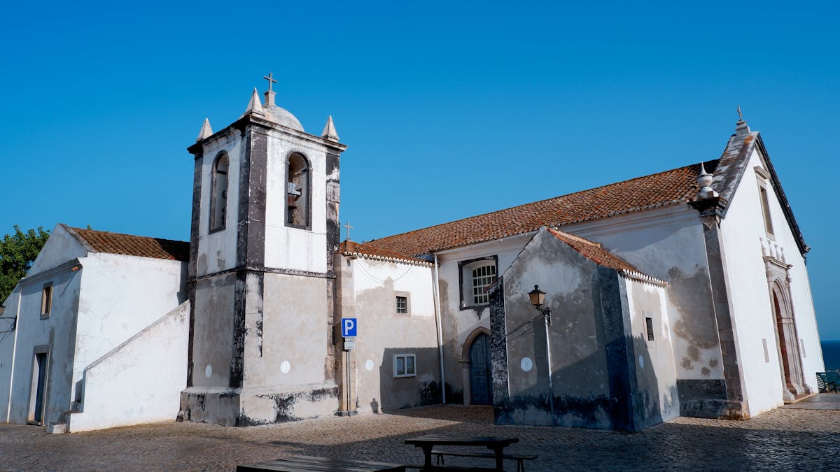 Sunlit church with bell tower in Cacela Velha Portugal under a clear blue sky