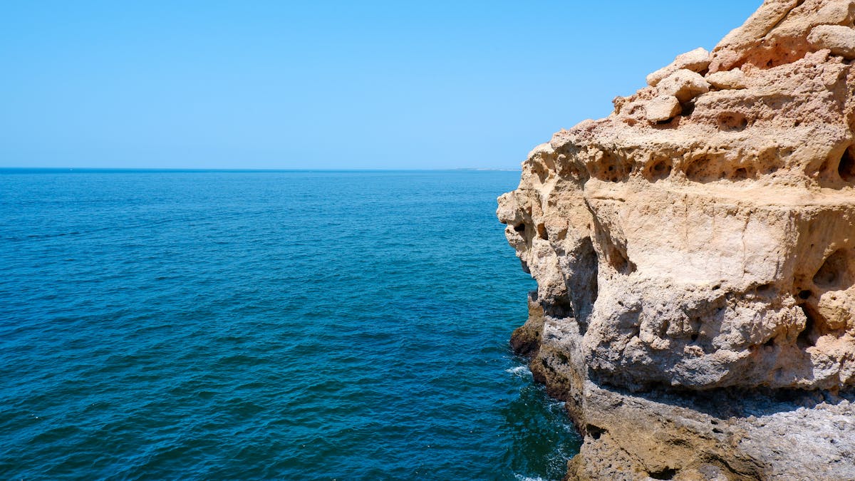 Dramatic limestone cliffs meeting clear blue Atlantic waters along the Algarve coast
