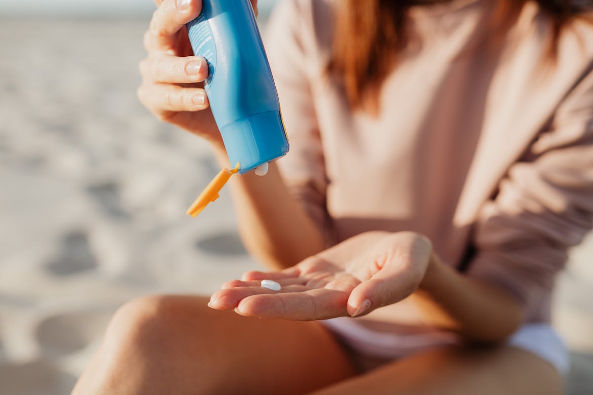 A person applies sunscreen at the beach on a sunny day