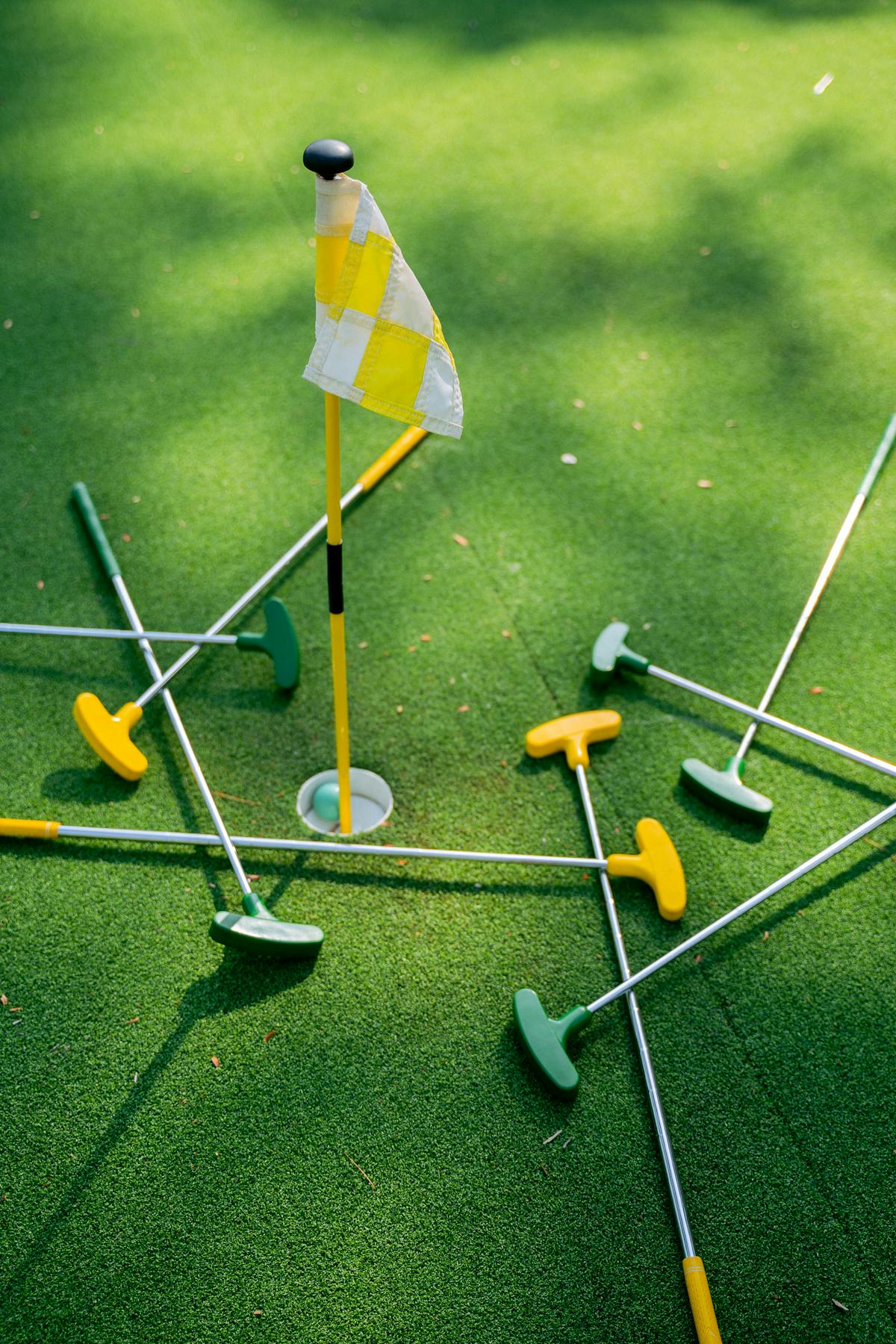 A colorful mini golf course with putters scattered around a flag