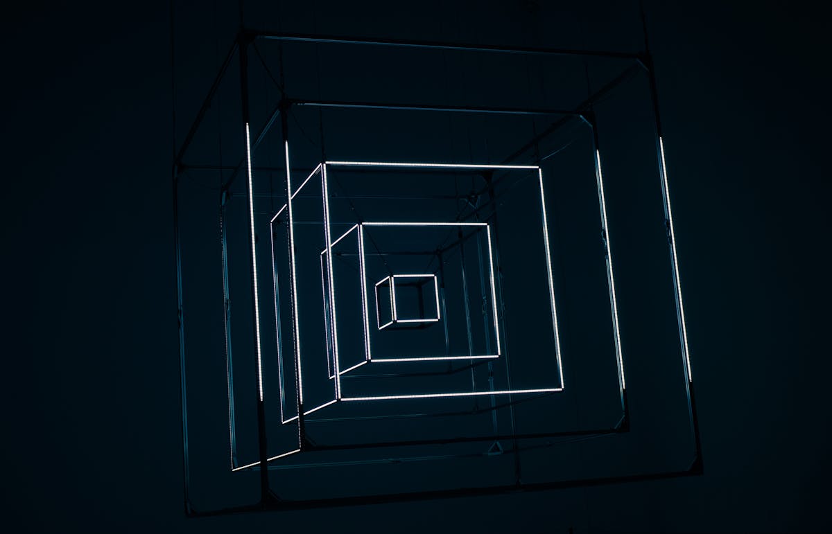 Modern art installation featuring geometric neon light shapes in a dark setting
