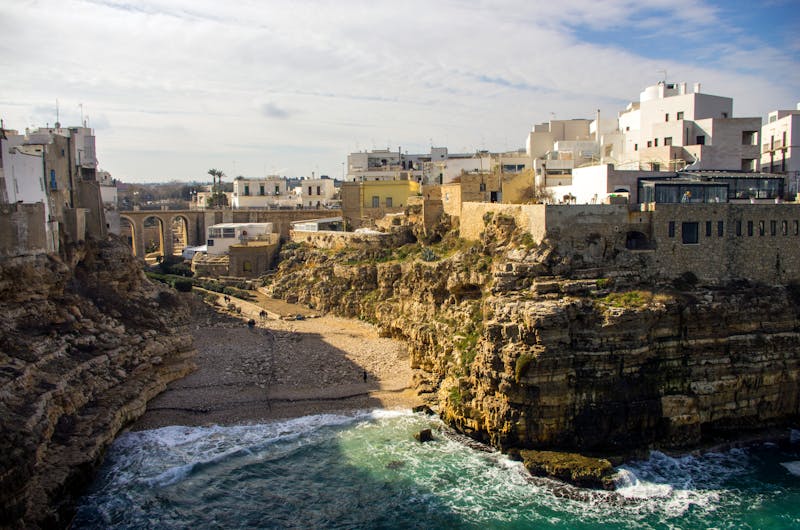 White and cream buildings perched on cliffs above the Mediterranean sea in Polignano a Mare