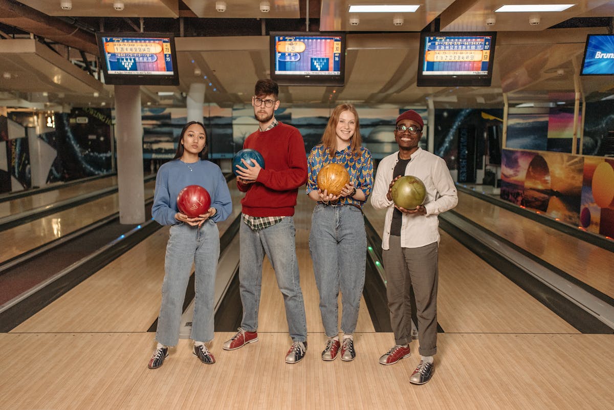 A diverse group of friends holding colorful bowling balls at an indoor bowling alley