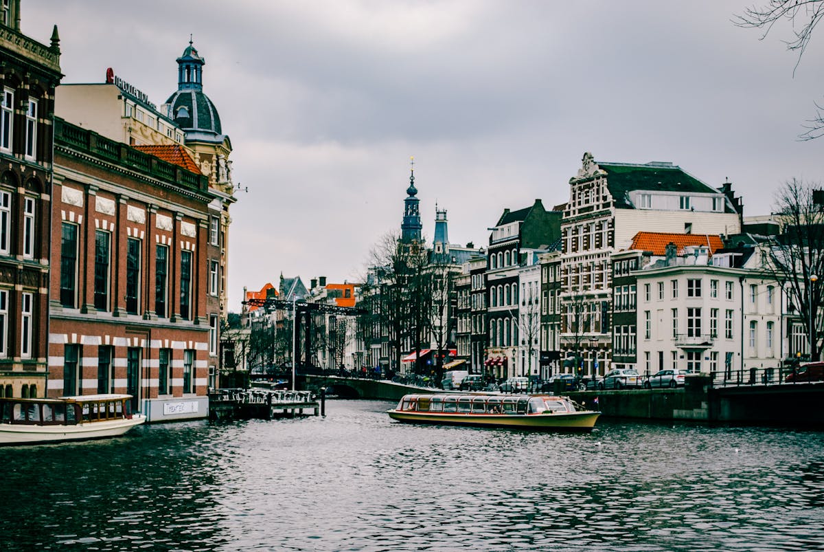 Classic Amsterdam canal scene with passing boat and traditional Dutch architecture
