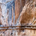 Hikers exploring the dramatic walkway of Caminito del Rey canyon trail in Spain