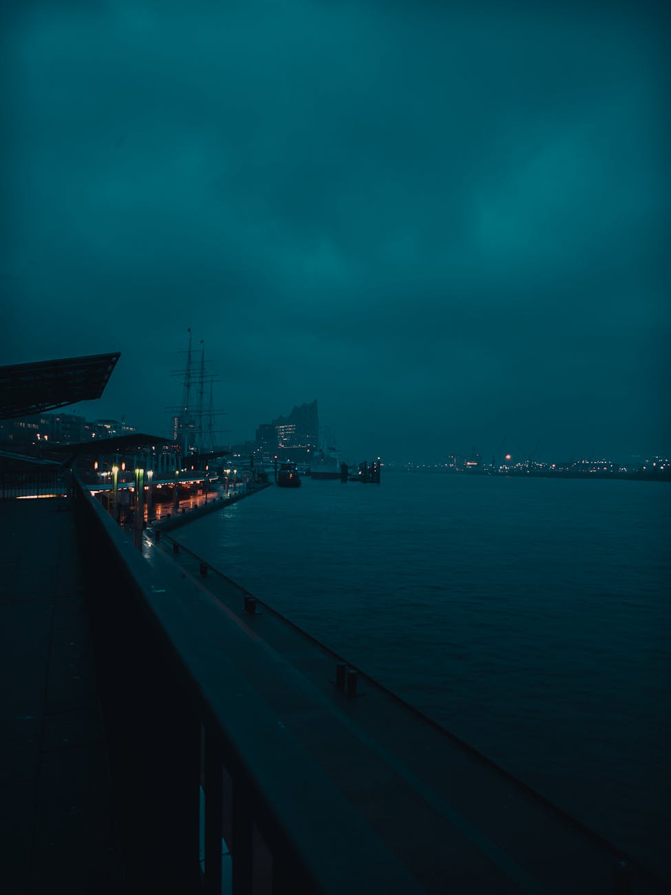 Moody evening view of Hamburg harbor with city lights reflecting on water