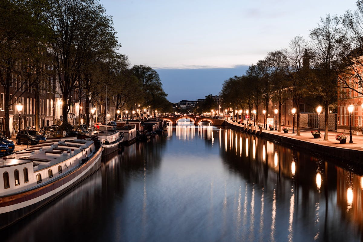 Peaceful evening scene of an Amsterdam canal with illuminated streets and boats
