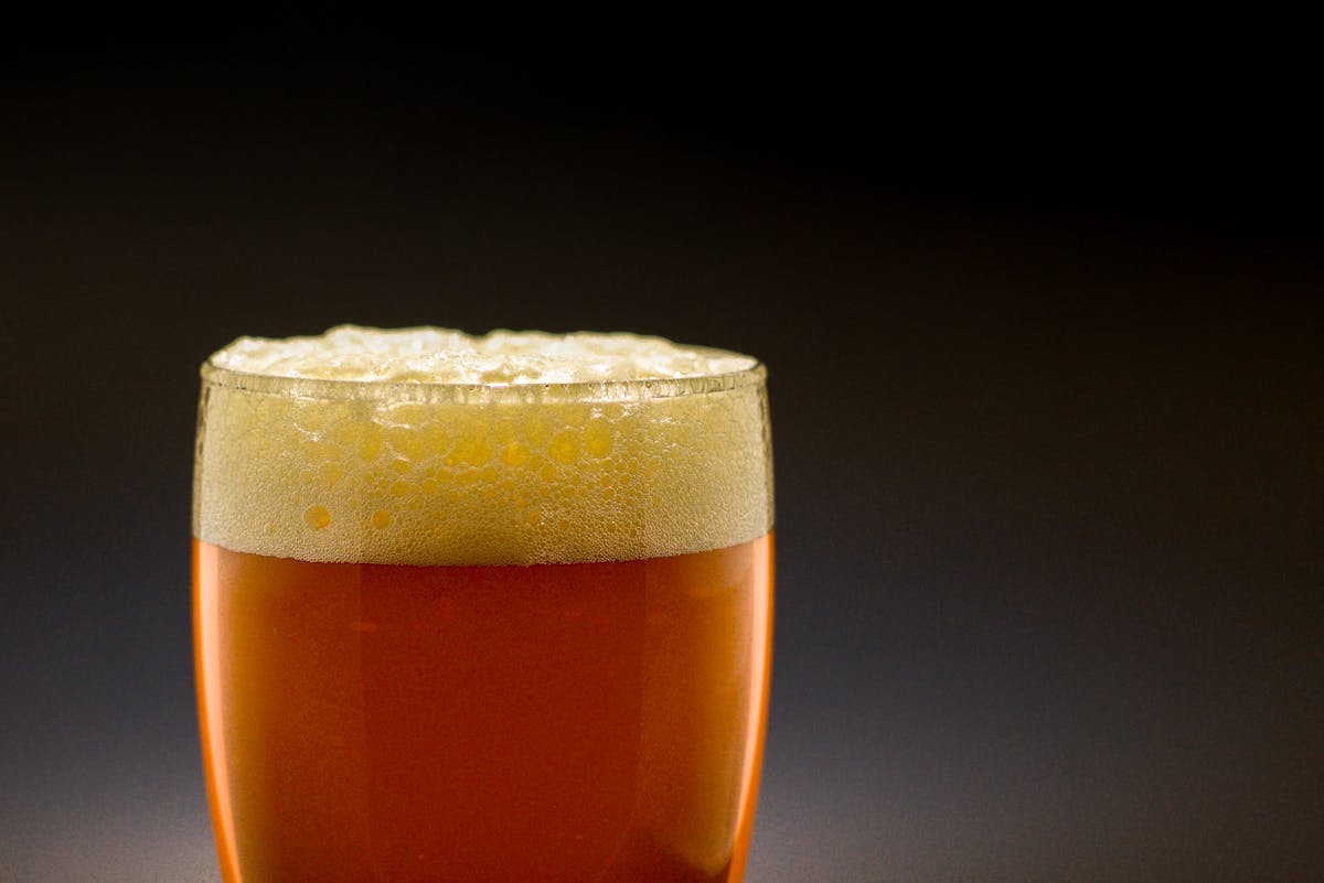 Close-up of amber beer in a glass with bubbles against a dark background