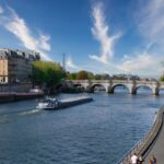 Eiffel Tower and Seine River with historical Parisian architecture under blue skies