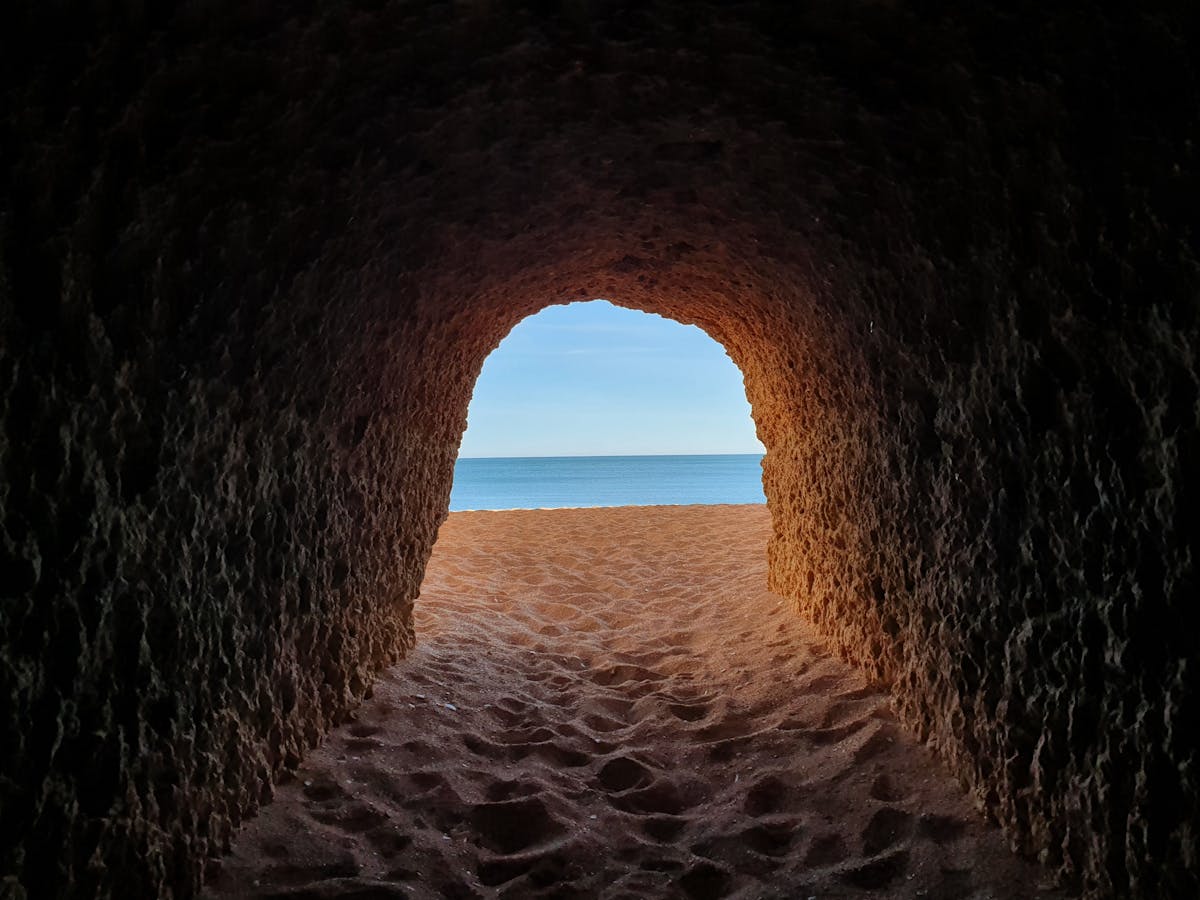 View from a cave tunnel leading to a pristine Algarve beach in Portugal