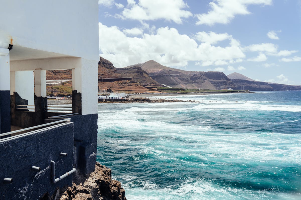 Coastal view of Gran Canaria with ocean waves crashing against the shore under sunny skies