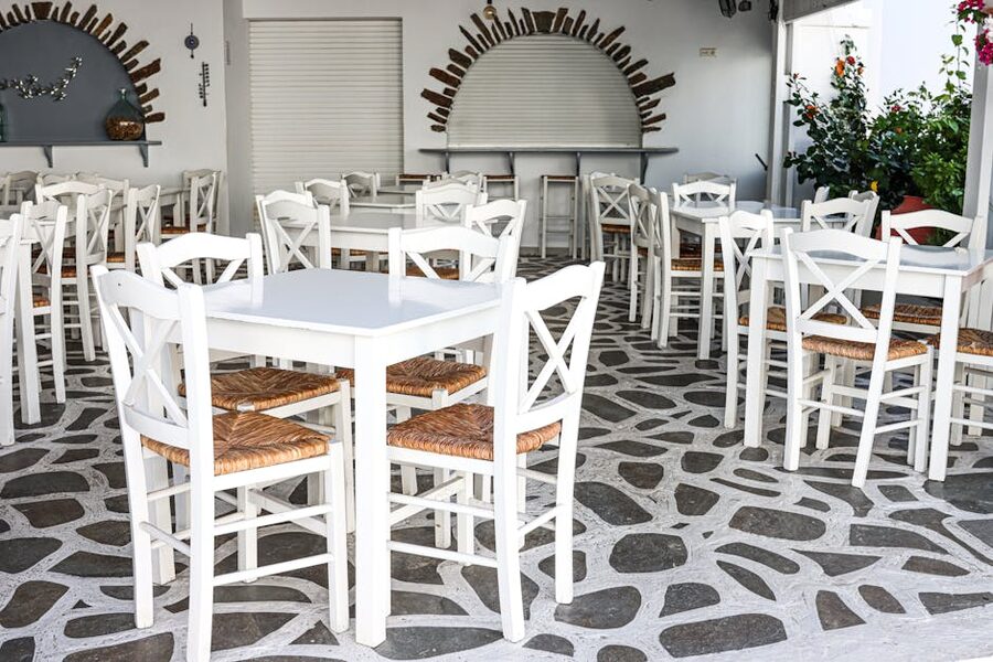 Traditional Greek cafe with white chairs and stone flooring in Naxos