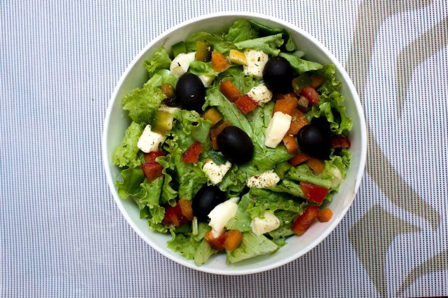 Bowl of fresh Greek salad with lettuce, black olives, cheese, and vegetables