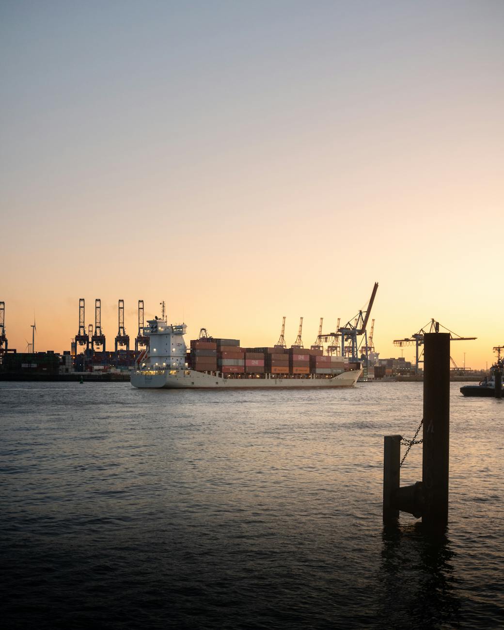 Container ship in Hamburg harbor at sunset with warm golden light