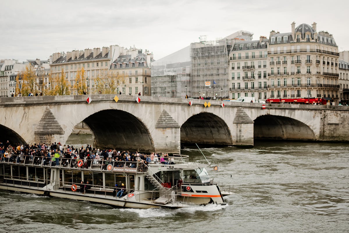 Tourists on a Seine River sightseeing cruise passing under Parisian bridges