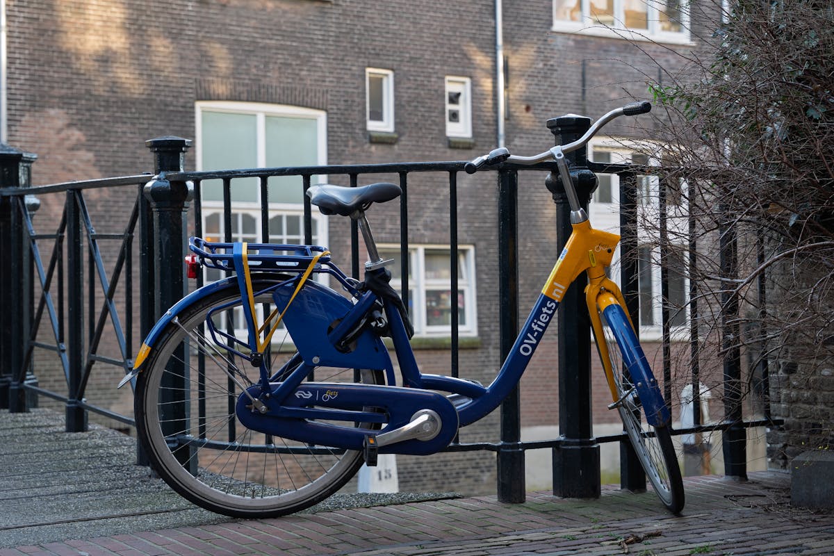 A blue rental bike parked on a bridge in Amsterdam