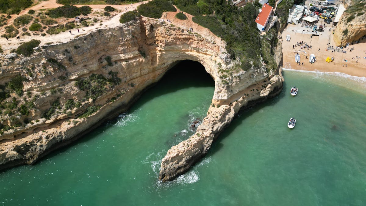 Aerial shot of Benagil Cave with turquoise waters and sandy beach in Algarve