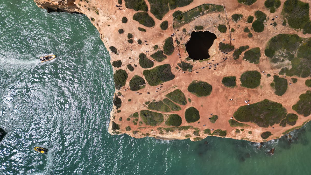 Dramatic aerial shot of the Algarve coastline with a natural cave arch