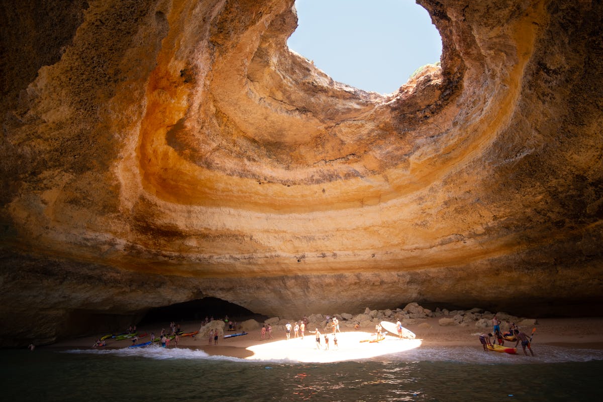 Interior of Benagil sea cave with sunlight illuminating sandy beach through dome opening