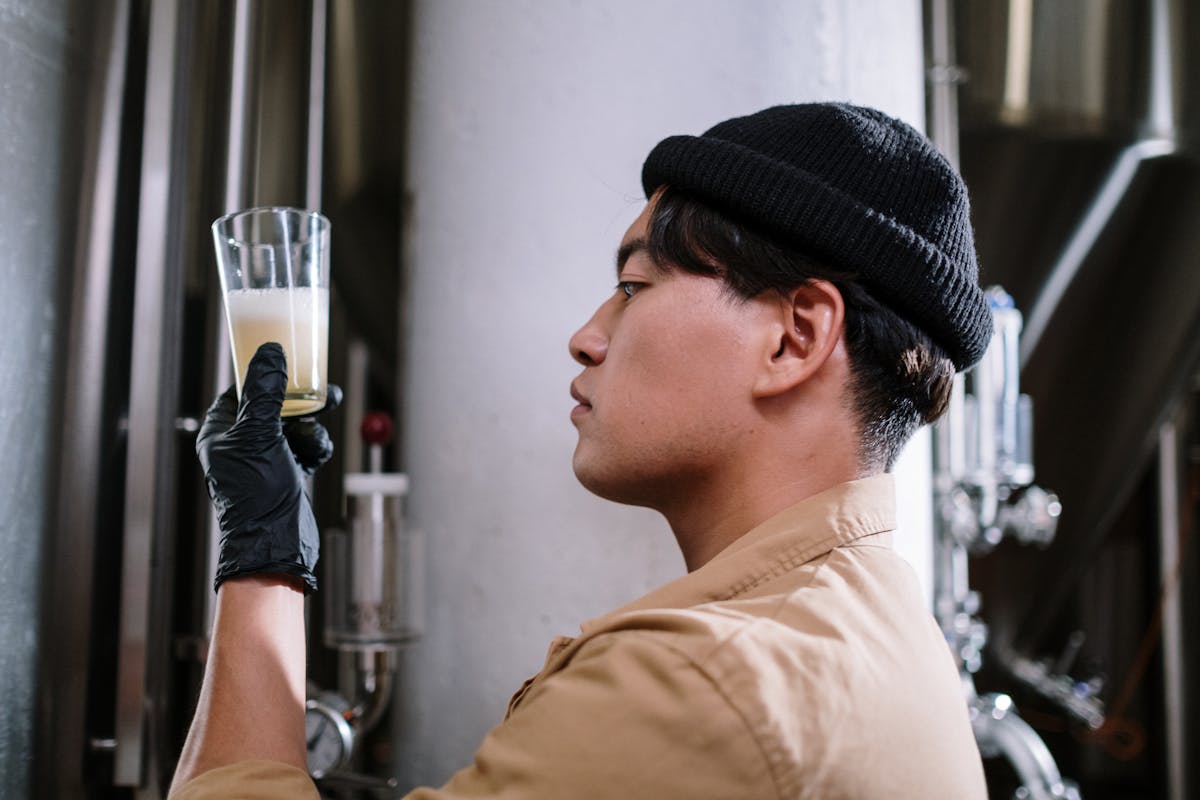 A brewmaster inspects craft beer in a glass at a brewery