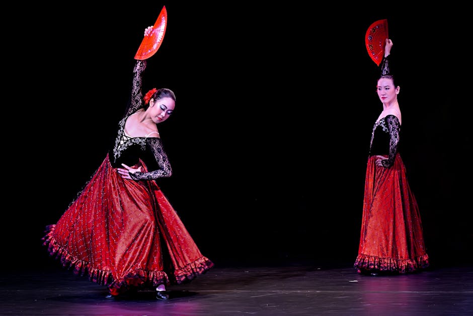 Two flamenco dancers performing with red fans in a dramatic pose