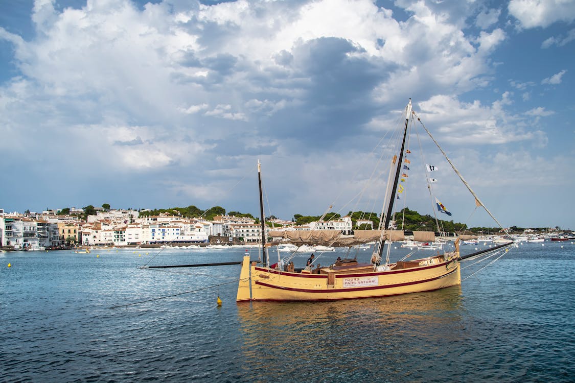 A picturesque harbor featuring a classic wooden sailboat under a blue sky