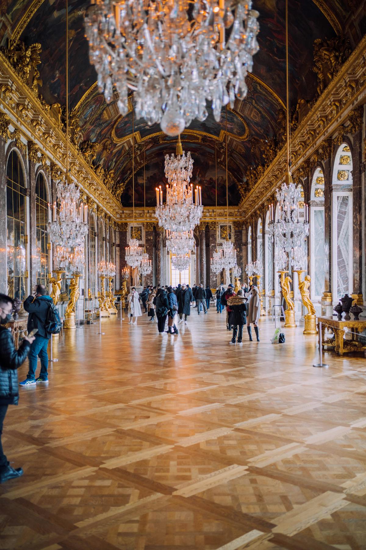 Visitors walking through the gilded Hall of Mirrors at the Palace of Versailles