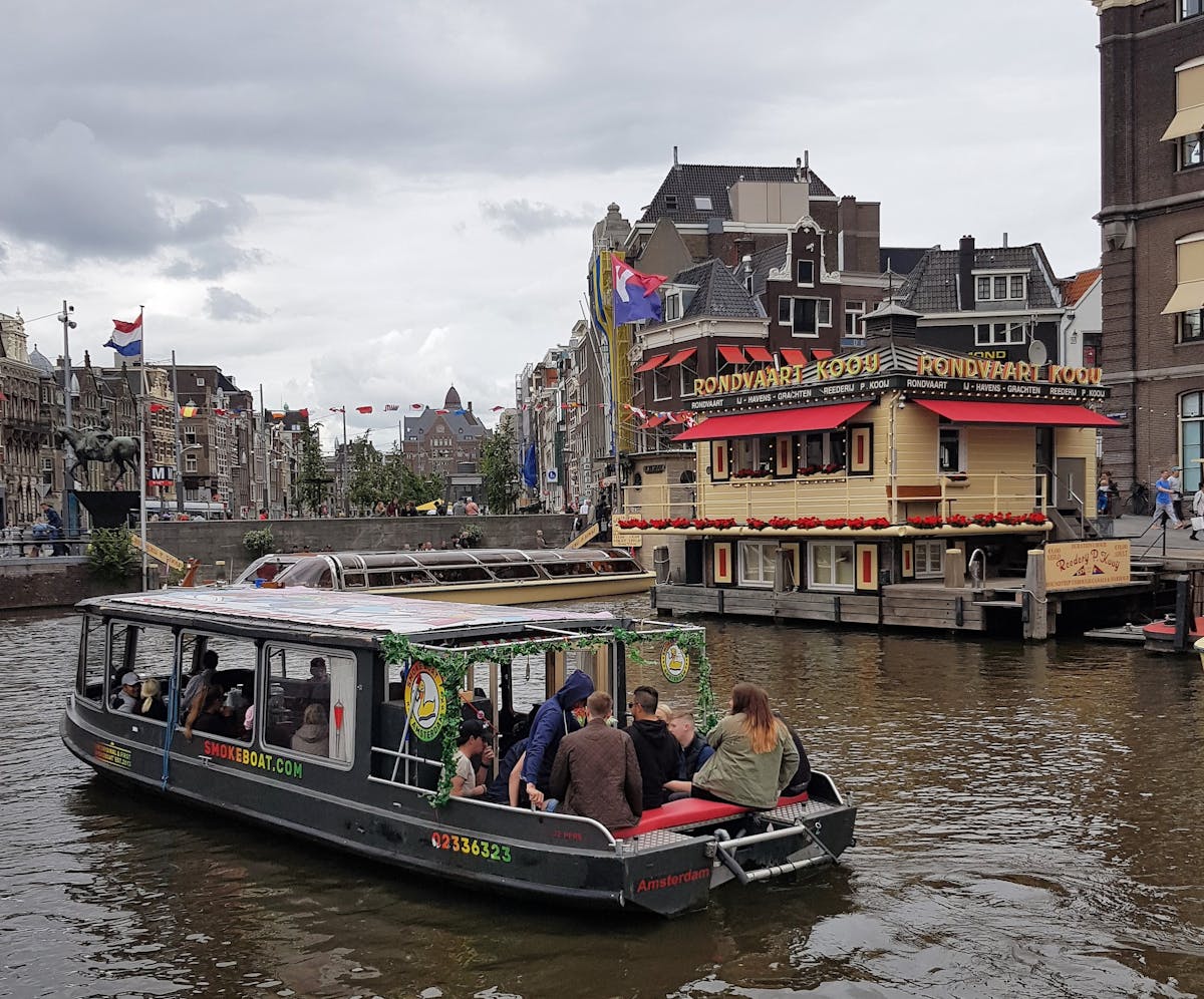 People enjoying a canal cruise in Amsterdam with iconic Dutch architecture in the backdrop
