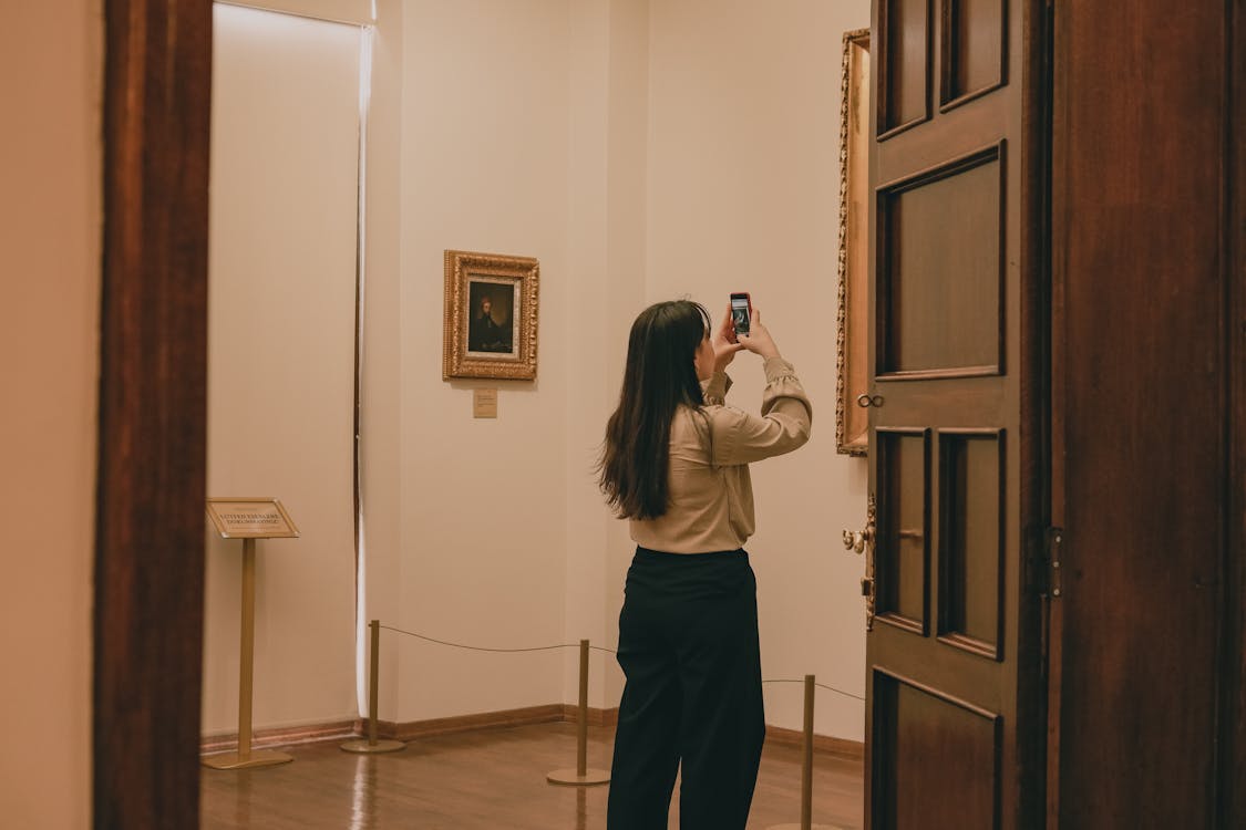Woman capturing artwork with phone in a tranquil museum setting