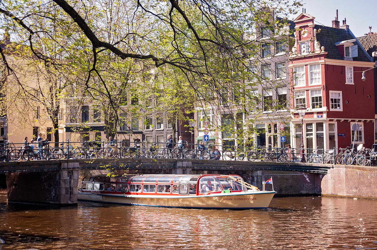 A tour boat passes under a classic Dutch bridge on an Amsterdam canal