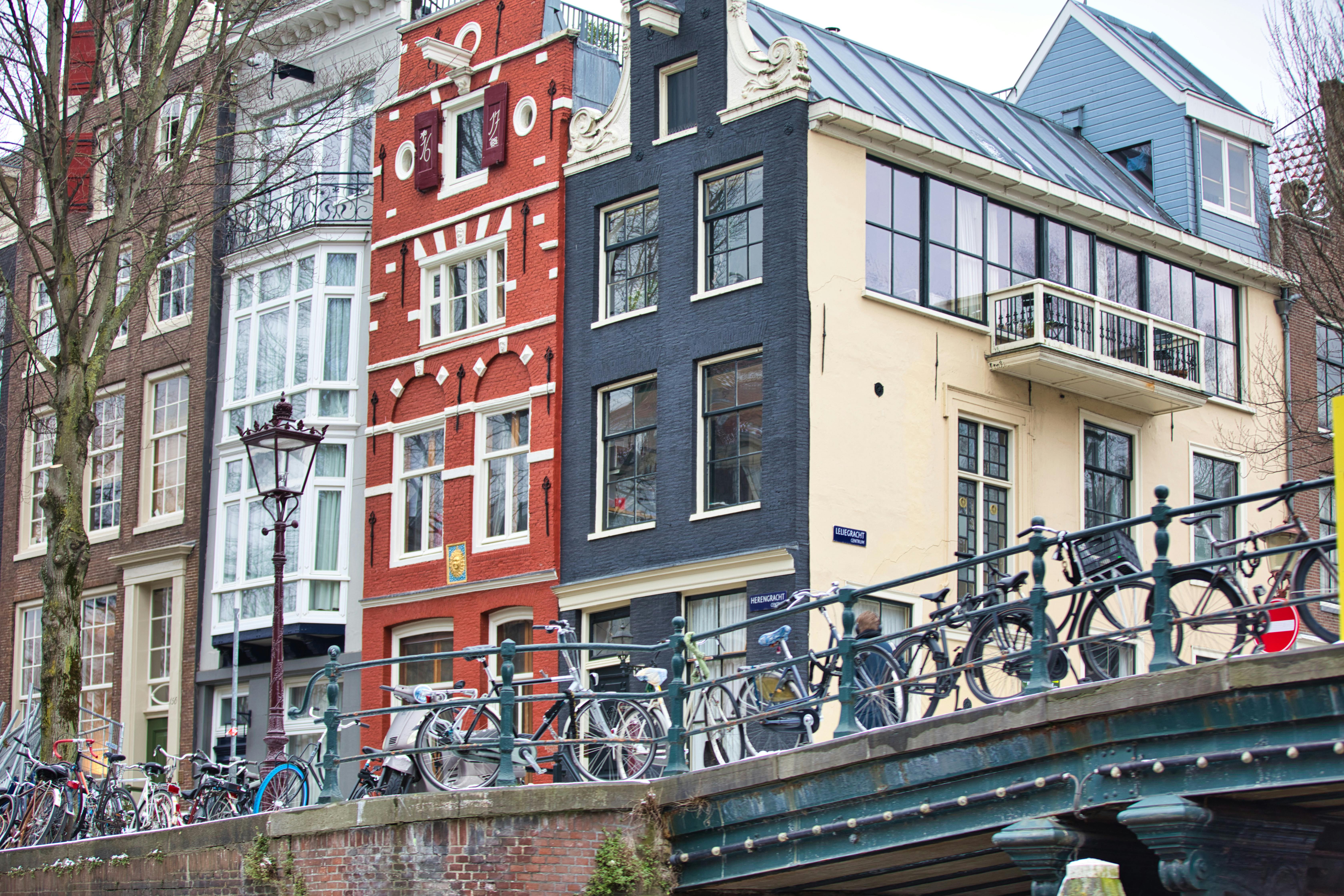 Bicycles lined along a bridge railing in Amsterdam with historic buildings in background