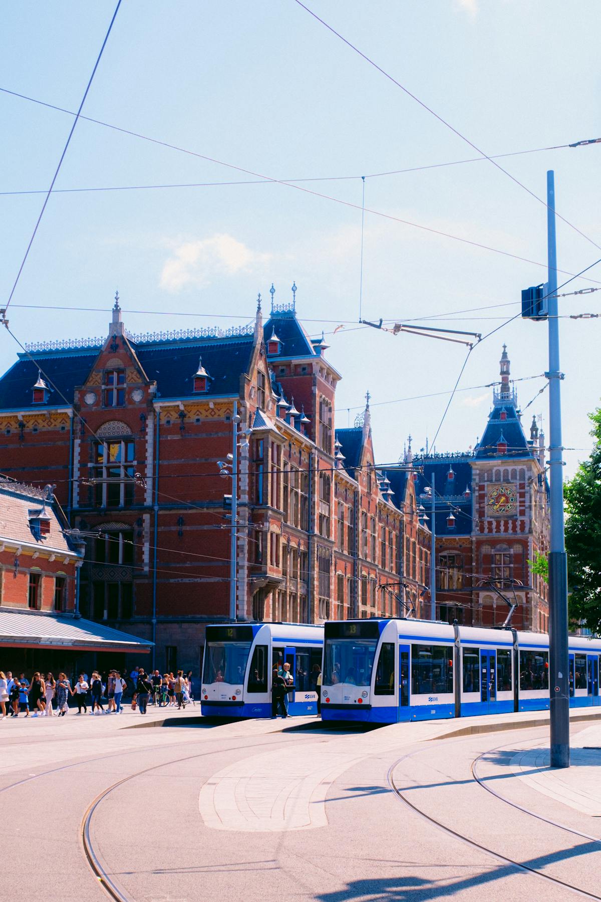 Classic Amsterdam street view with trams passing by historic buildings under a blue sky