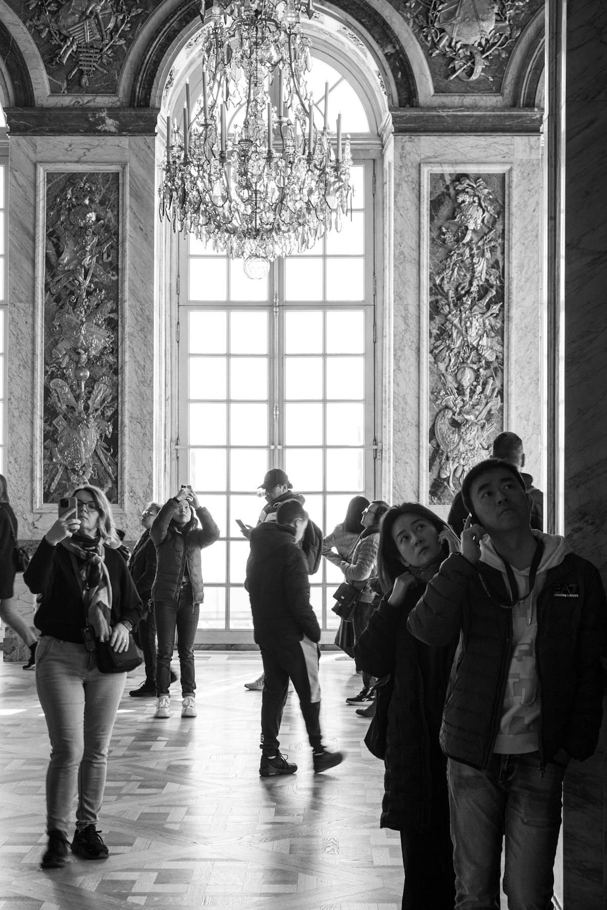Tourists exploring the grand Hall of Mirrors with ornate golden details at Versailles