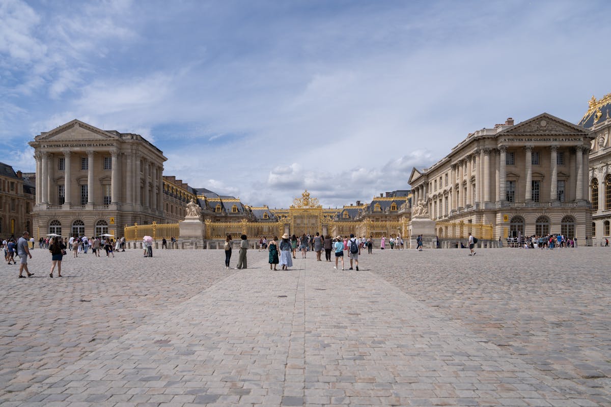 Tourists walking through the grand courtyard of the Palace of Versailles