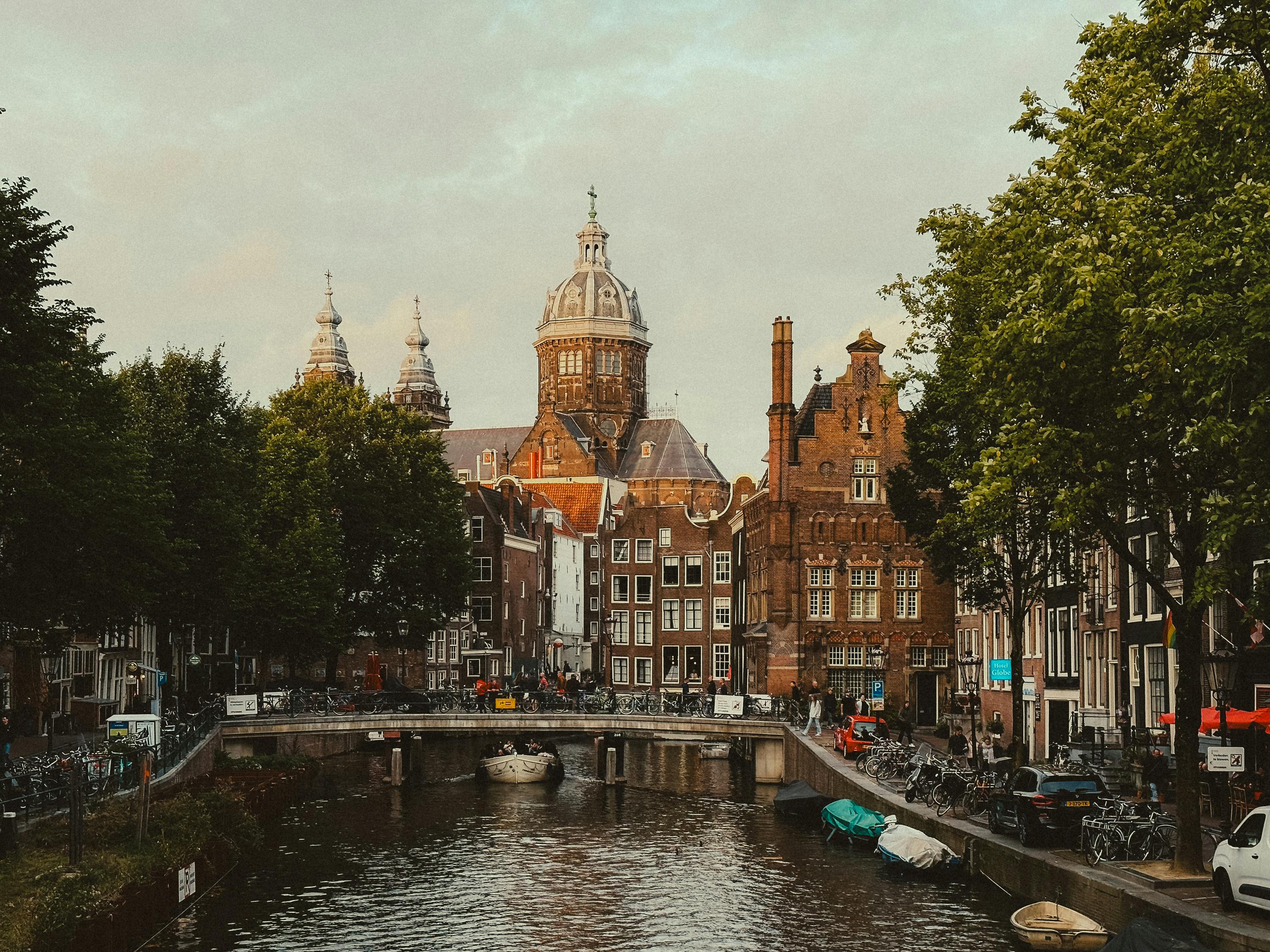 Amsterdam canal scene with iconic Dutch architecture and lush green trees