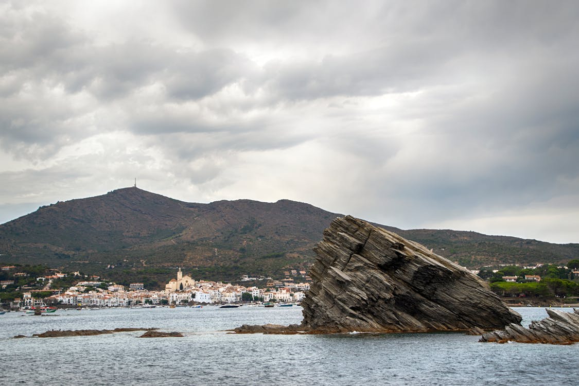 Dramatic rock formation near Cadaques with cloudy sky and mountainous backdrop