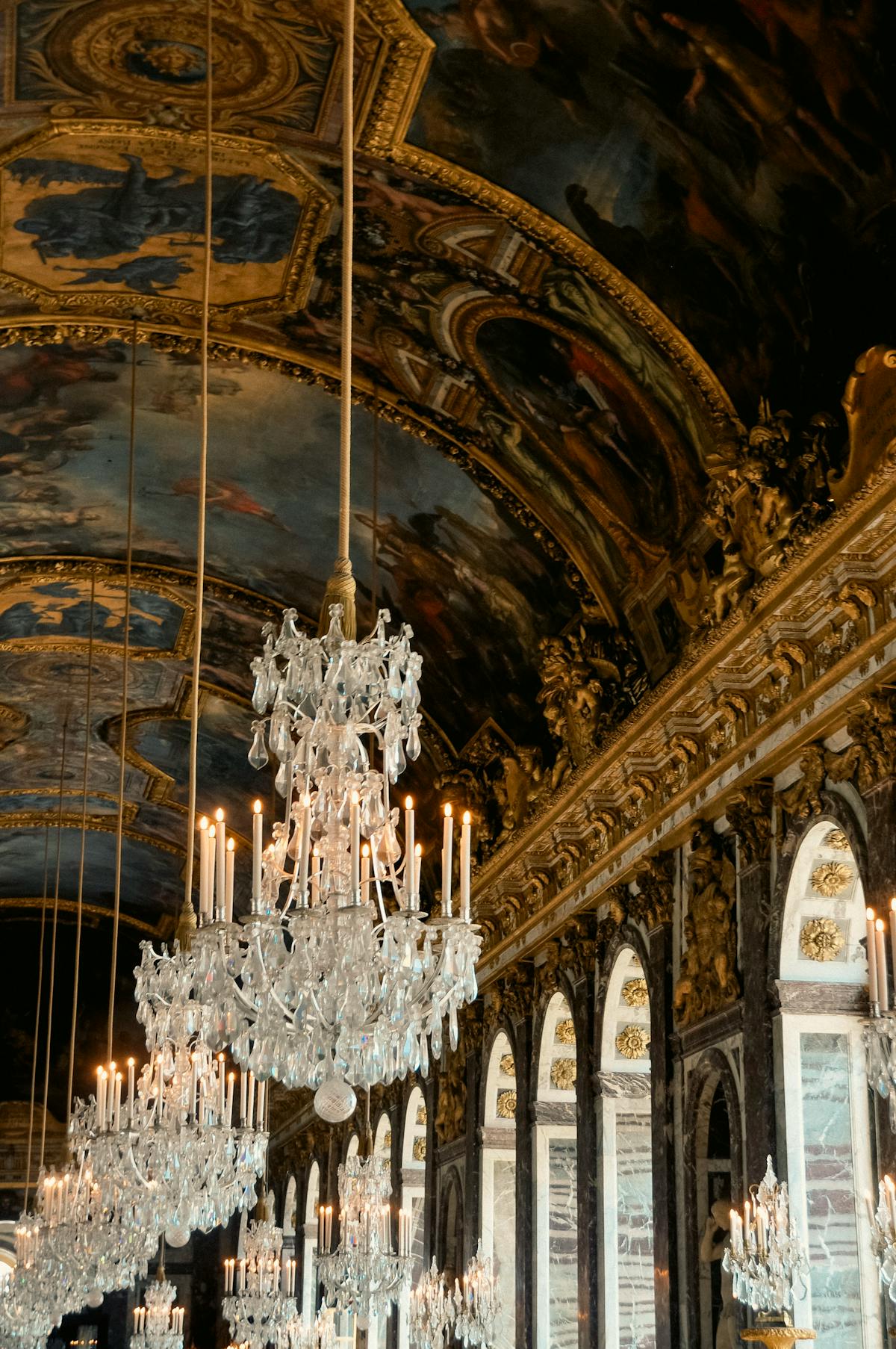 Stunning baroque ceiling with ornate chandeliers inside the Palace of Versailles