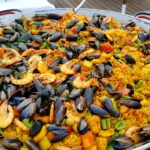 Close-up of a large pan of colorful seafood paella outdoors