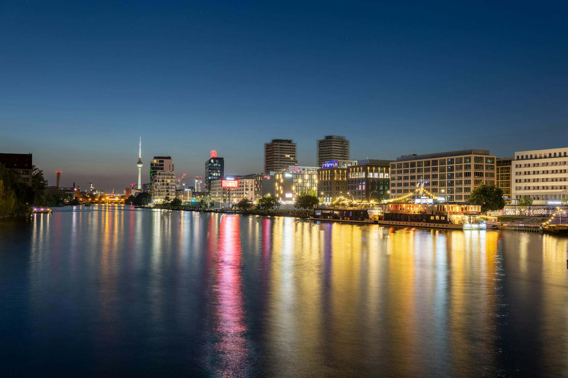Illuminated Berlin cityscape reflecting on the Spree River during twilight