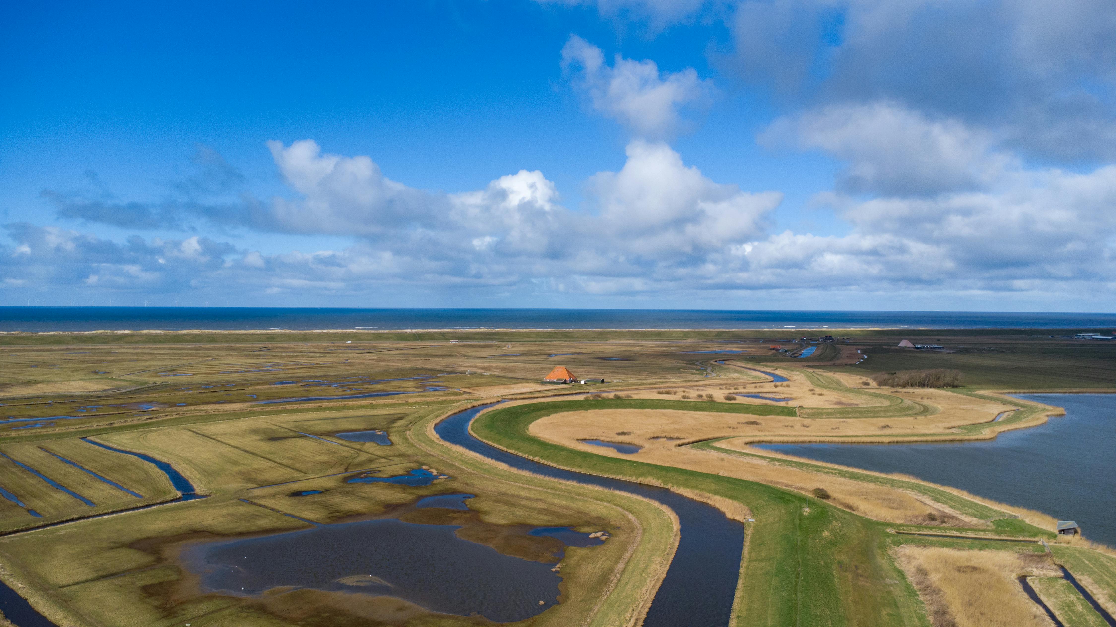 Aerial view of scenic Dutch coastal landscape with green fields and waterways