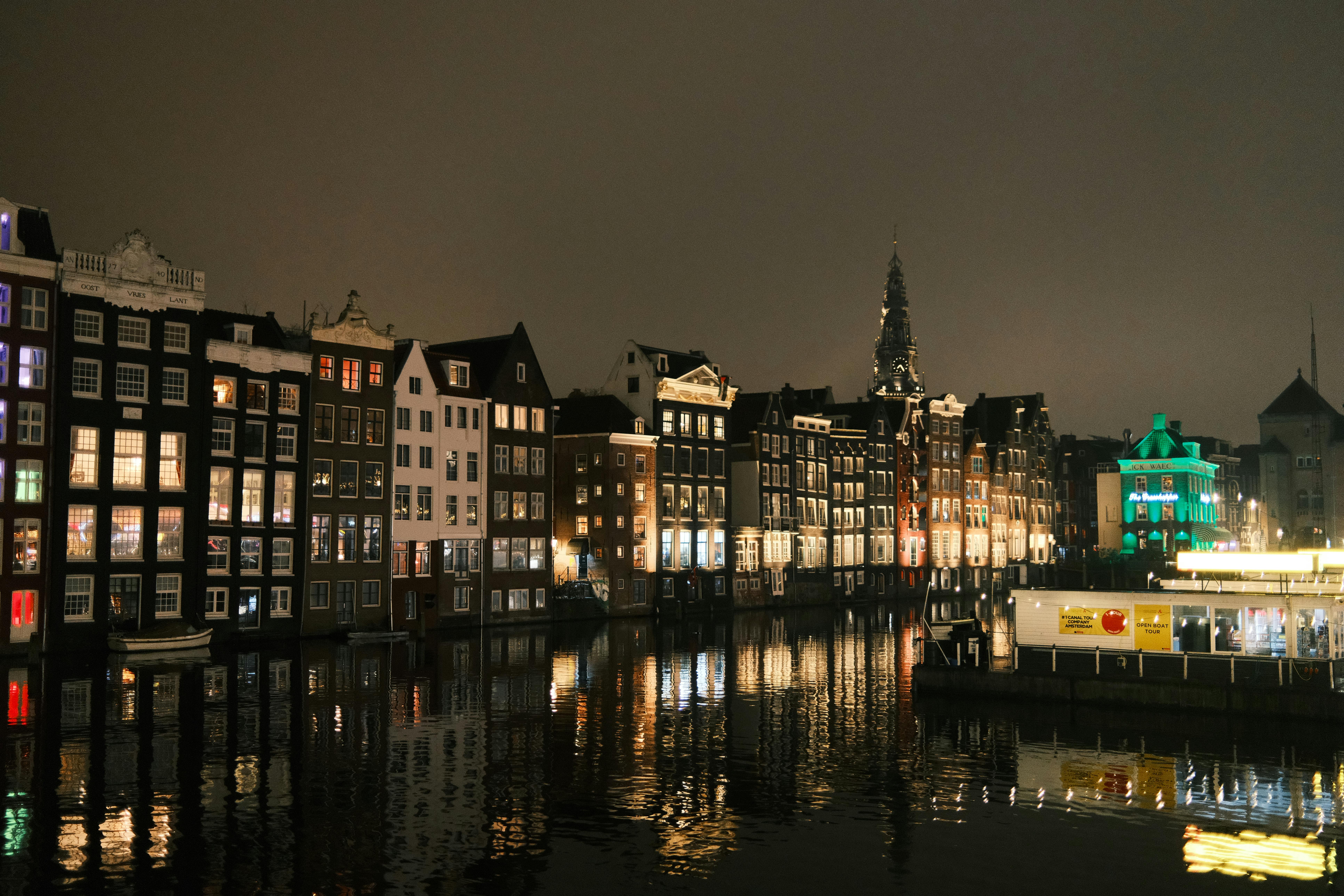 Historic Amsterdam canal houses illuminated at night reflecting in calm water