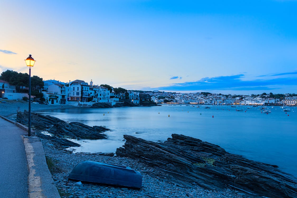 Peaceful evening scene of Cadaques seaside with illuminated homes along the bay