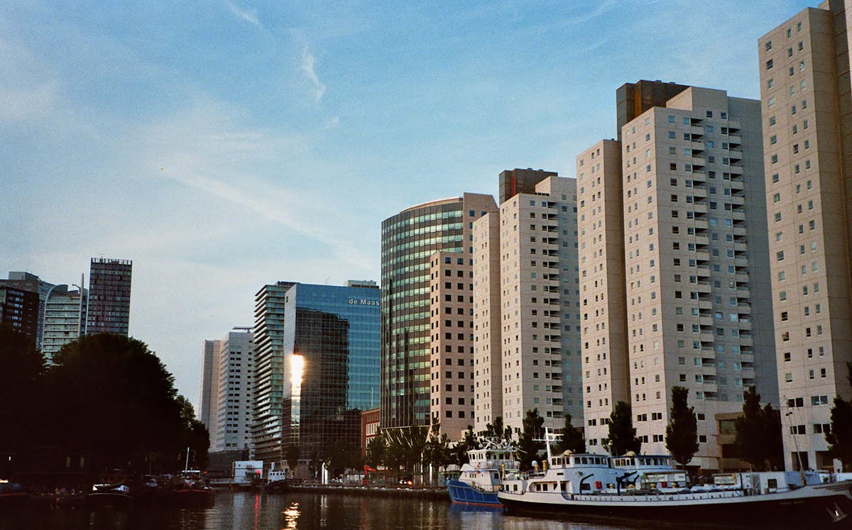 Modern high-rise buildings line the Rotterdam waterfront under a clear blue sky